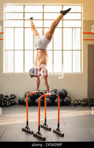 Side view of strong male performing calisthenics frog stand exercise on ...