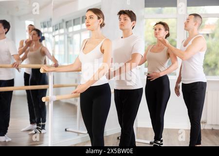 Ballet students practicing basic positions at barre with instructor ...