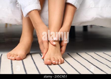 Young woman making foot massage on floor indoors, closeup Stock Photo ...