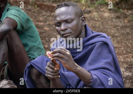 Mursi Tribe (Ethiopia) gathered around fire place, preparing, sharing ...