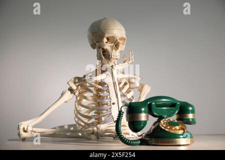 Waiting concept. Human skeleton at grey marble table with corded ...