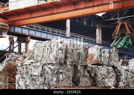 Scrap yard, pressing non-ferrous scrap metal into a cube. Recycling of ...