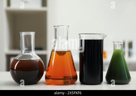 Flasks and beaker with different types of crude oil on light grey table ...