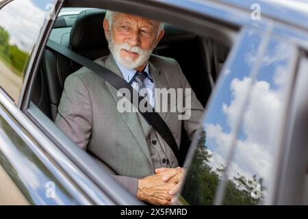 Dignified elderly man with a beard smiles warmly from the drivers seat ...