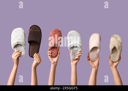 Female hands holding different slippers on lilac background Stock Photo ...