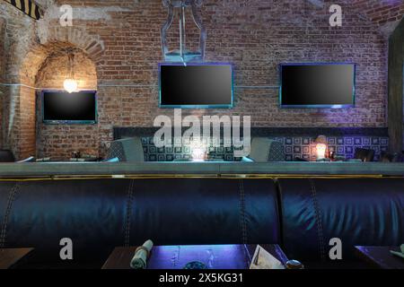 Restaurant tables with lamps under flat screen TVs Stock Photo - Alamy