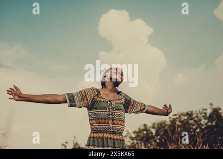 Nigeria, Delta state, Smiling woman in patterned dress against sky ...