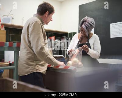 Volunteer giving man vegetables in community food center Stock Photo ...