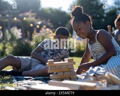 Siblings (2-3, 8-9, 10-11) playing block removal game Stock Photo - Alamy