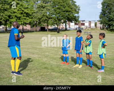 Coach giving prizes to kids (8-9) on soccer field Stock Photo - Alamy