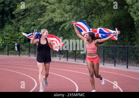 Two female athletes running with flags on running track Stock Photo - Alamy