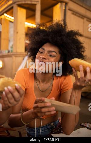 Two young latin people eating traditional arepas in the living room ...