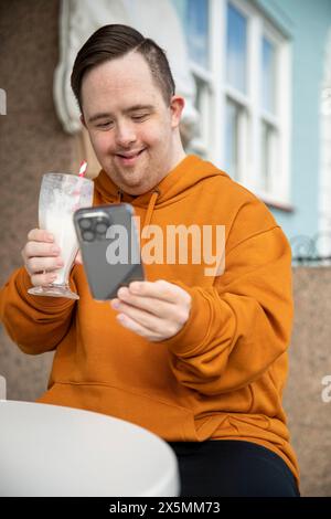Man drinking milkshake in sidewalk cafe Stock Photo - Alamy