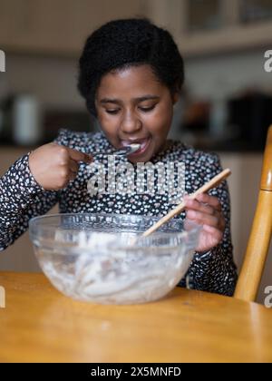 Girl eating cookie batter from bowl Stock Photo - Alamy