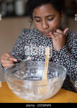 Girl eating cookie batter from bowl Stock Photo - Alamy