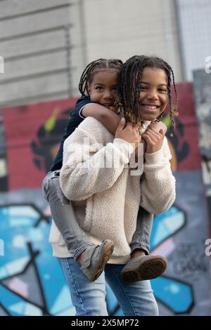 piggyback ride of younger child on elder sister in green field Stock ...