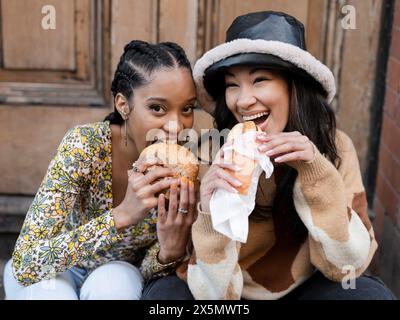 Two young women eating fast food Stock Photo - Alamy