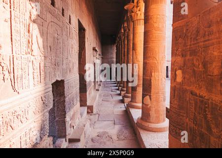 Colonnade featuring ancient wall carvings at Philae Temple in Aswan ...