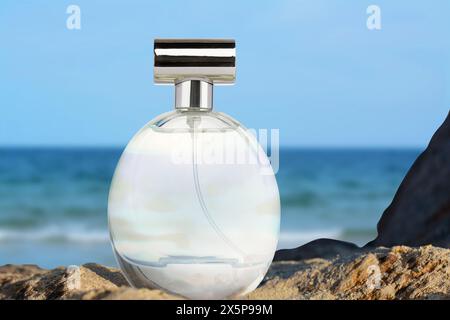Bottle of aquatic perfume on rock near ocean. Fresh sea breeze scent ...