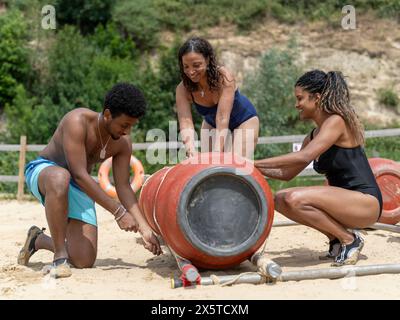 Friends building raft from barrels and ropes on beach Stock Photo - Alamy