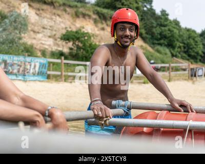 Friends standing with raft in lake Stock Photo - Alamy