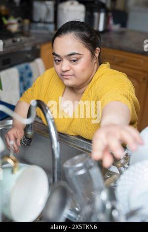 Young woman with down syndrome washing dishes at home Stock Photo - Alamy
