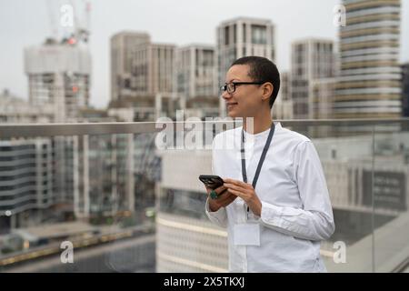 Non binary office worker posing against office buildings Stock Photo ...