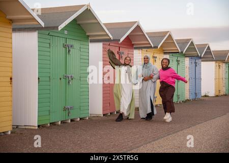 Cheerful Muslim friends walking next to beach huts Stock Photo - Alamy