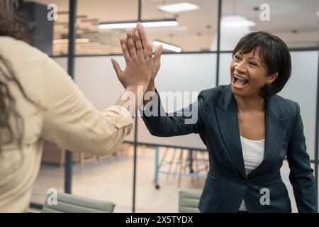 Businesswomen high fiving in office Stock Photo - Alamy