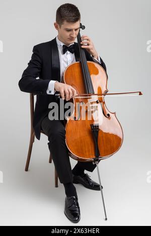 Passionate cello player sitting on chair performing concert Stock Photo ...