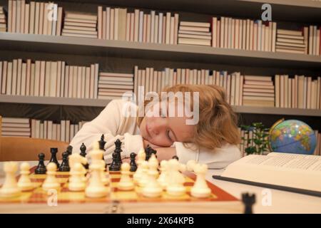 Tired and boring school. Tired kid think about chess game. Sleepy lod ...