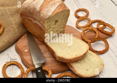 Bread, sliced bread and bagels lie on a cutting board on the table ...