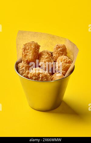 Metal bucket with chicken nuggets on yellow background Stock Photo - Alamy