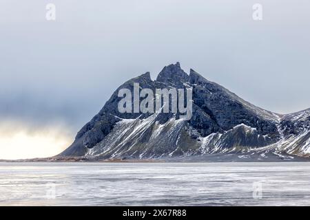 The Eystrahorn (Batman Mountain) in winter behind an icy bay in south ...
