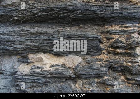 Gray structural stone wall of the ancient building consists of old dark ...