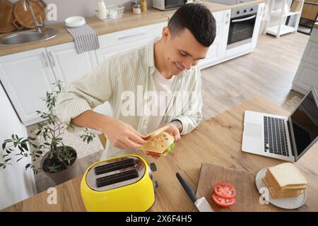 Young man making tasty sandwiches from toasts in kitchen Stock Photo ...