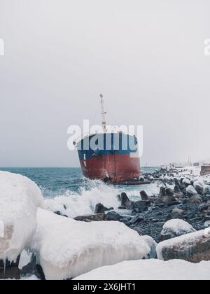 Cargo ship strands aground on a rocky shore after a storm, surrounded ...