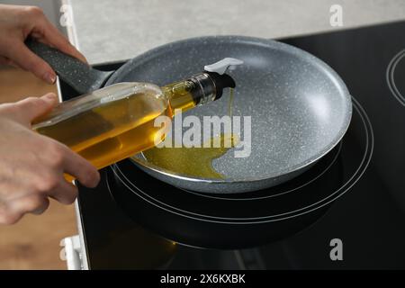 Vegetable fats. Woman pouring cooking oil into frying pan on stove in ...
