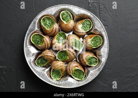 Delicious cooked snails on dark textured table, top view Stock Photo ...