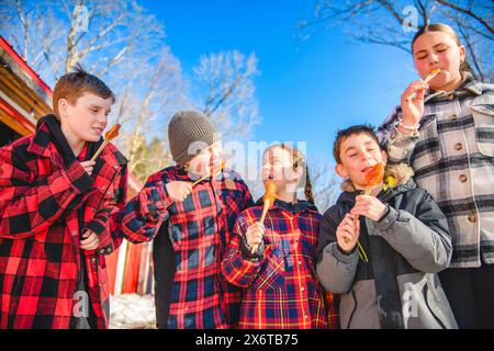 Photo showing children tasting maple syrup with wooden spoon Stock ...