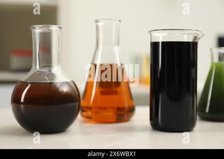 Flasks and beaker with different types of crude oil on light marble ...