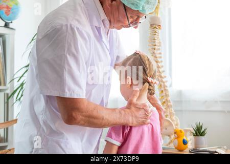 male Orthopedist doctor conducts spinal examination child, young girl ...
