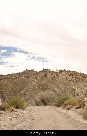 Steep rocky cliff with visible striations and sparse vegetation ...