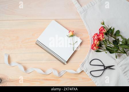 Blank diary with a pink rose, apron with a bouquet of flowers and ...