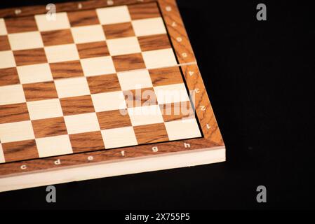 Part of an empty wooden checkers or chess board on a black background ...