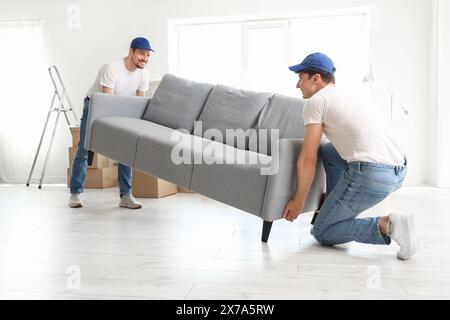 Loaders carrying sofa in room Stock Photo - Alamy