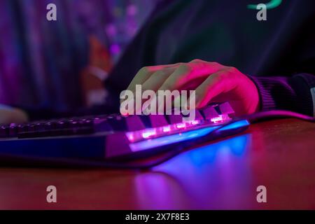 Professional online gamer hand fingers mechanical keyboard in neon ...