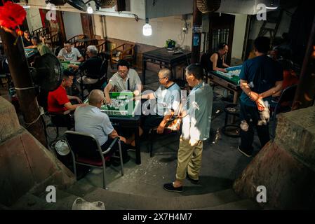 Lively Gathering of People Playing Mahjong in a Traditional Chinese ...