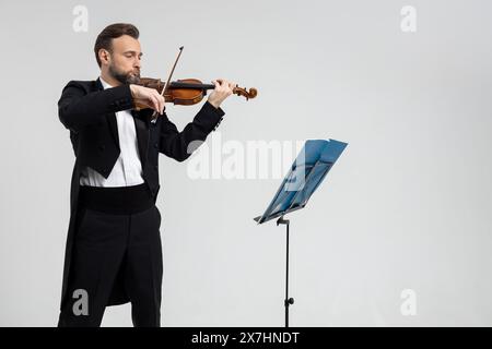 Violinist virtuoso in tuxedo performs melody on classical violin Stock Photo - Alamy