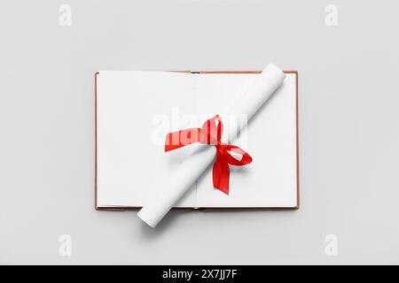 Diploma with red ribbon, opened book and graduation hat on white ...
